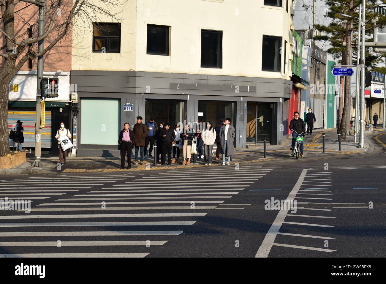 People waiting in front of a pedestrian crossing during sunset at an ...