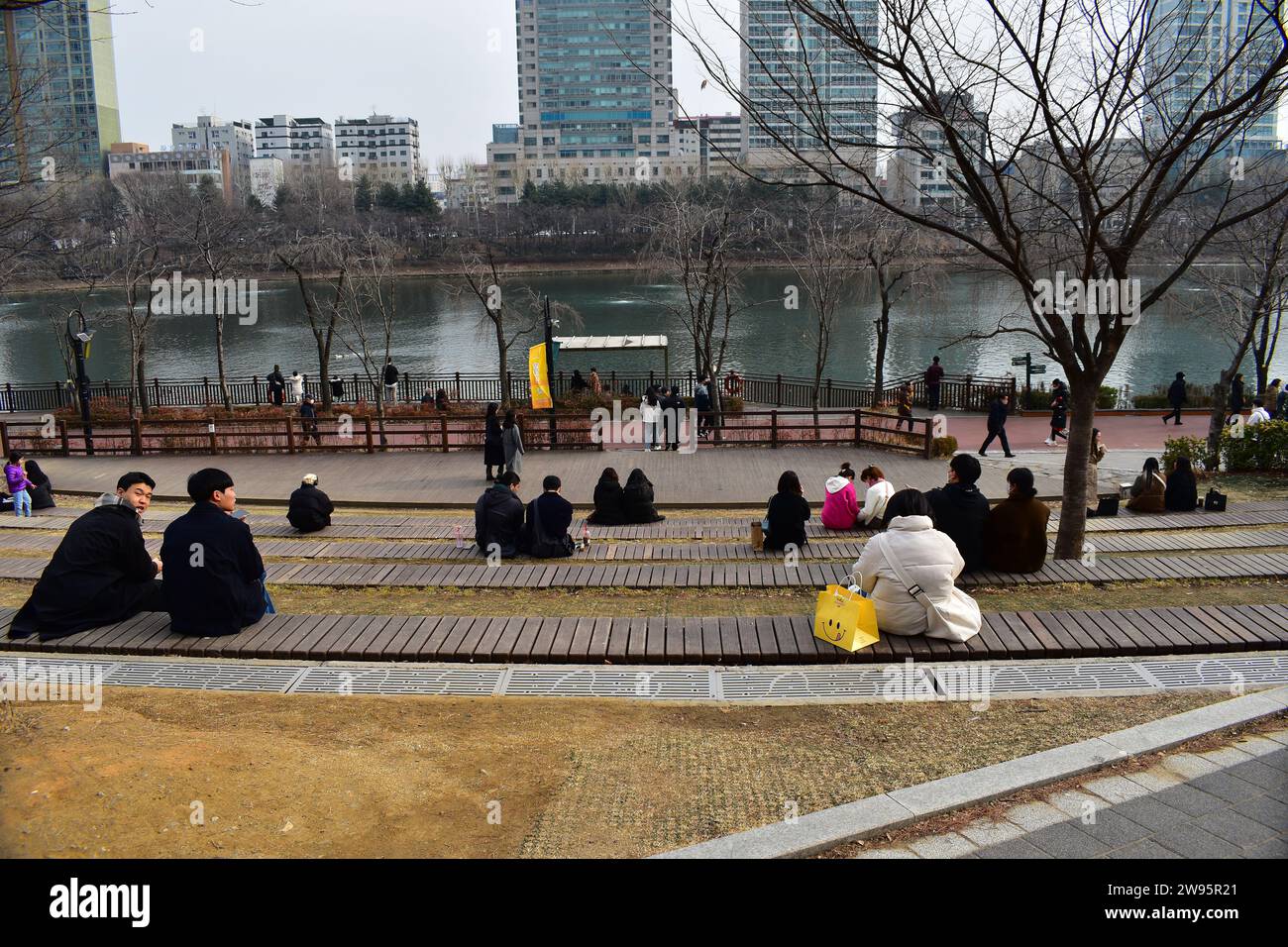 People sitting in the park around Seokchon Lake near Lotte World Tower ...