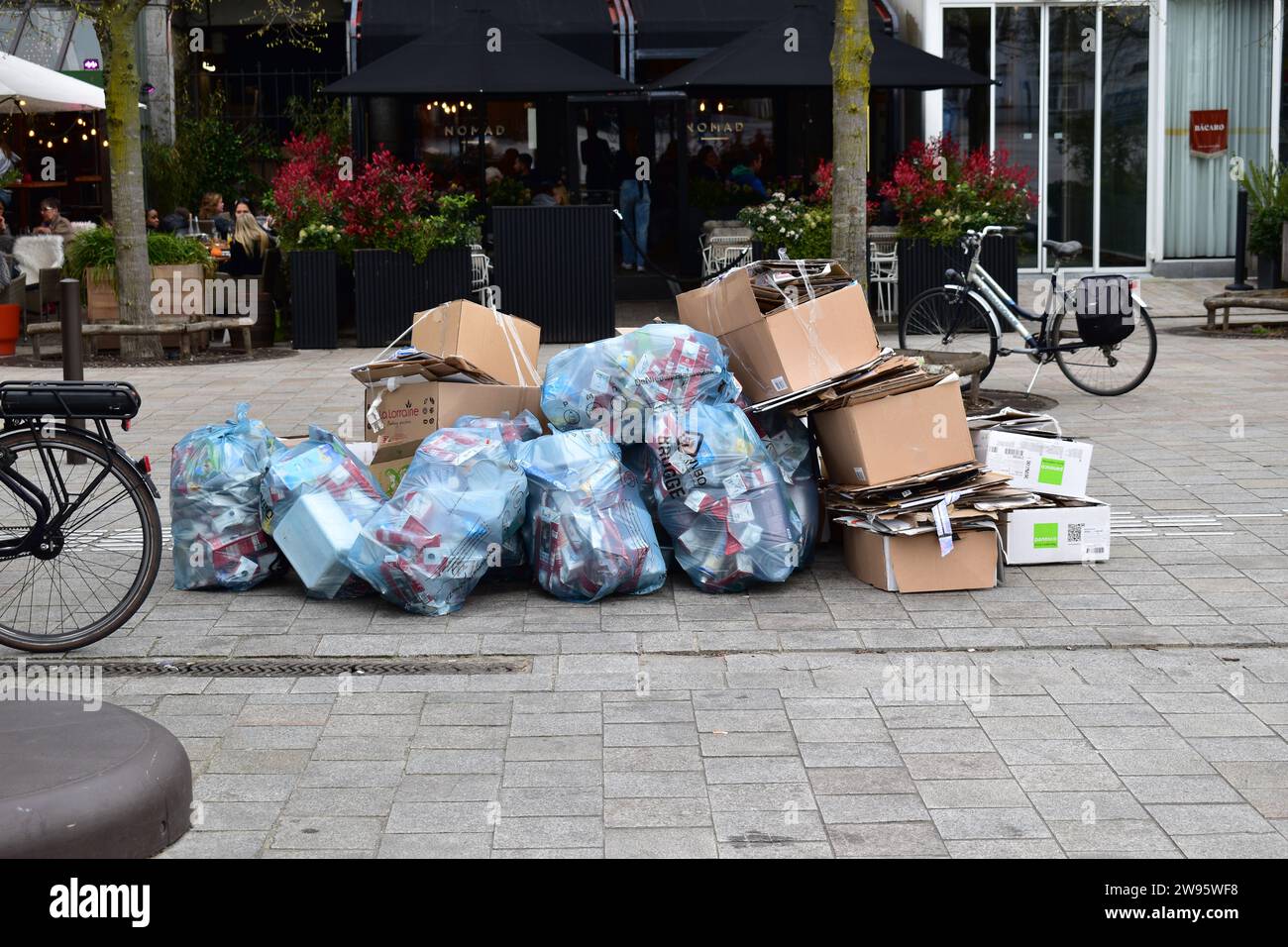 A pile of cardboard boxes and blue garbage bags containing cans and ...