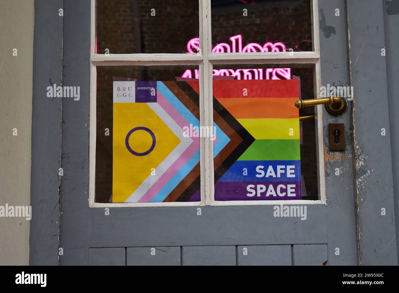 A LGBTQI+ flag behind a window in a door that leads to a safe space ...