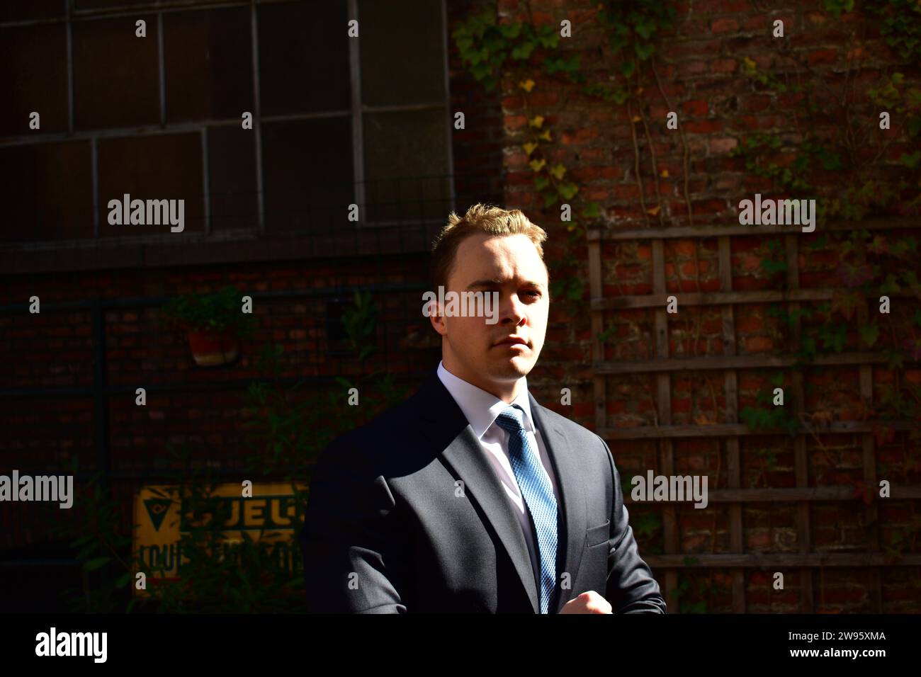 Young muscular white man wearing a full black suit, white collared ...