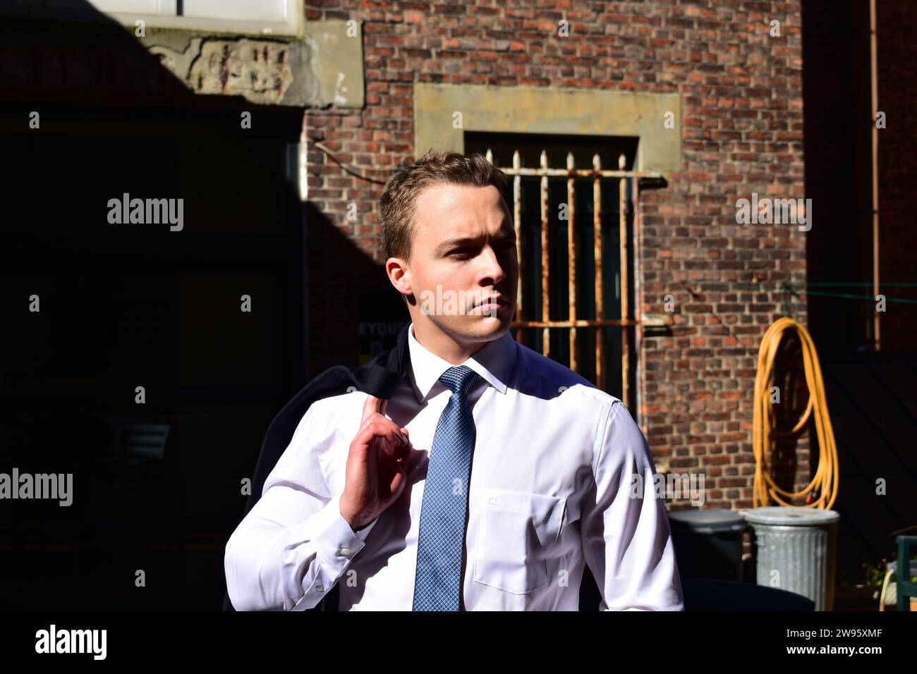 Young muscular white man carrying his black suit jacket over his ...