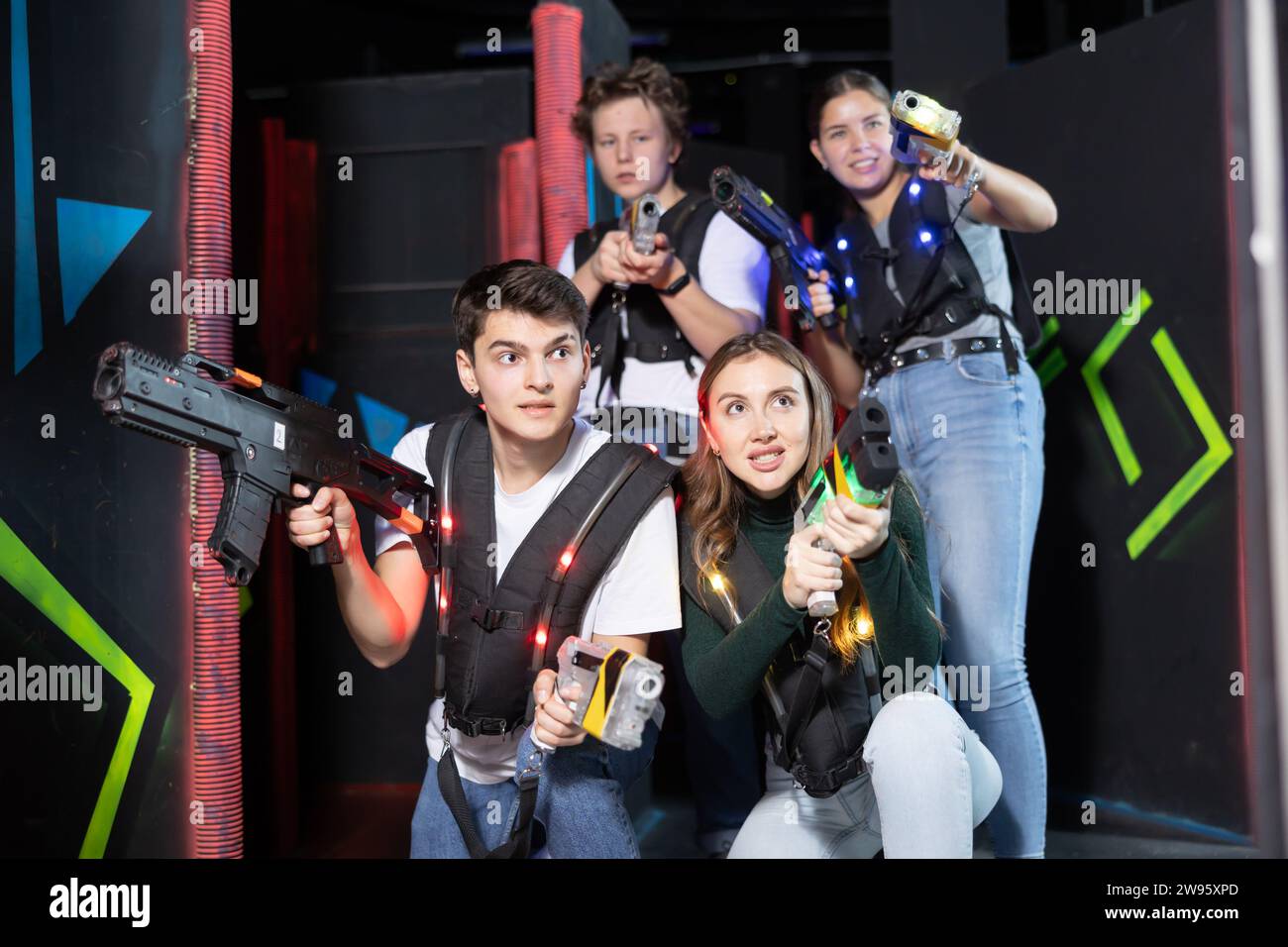 Laser tag players young mens and womens playing in teams in dark laser ...