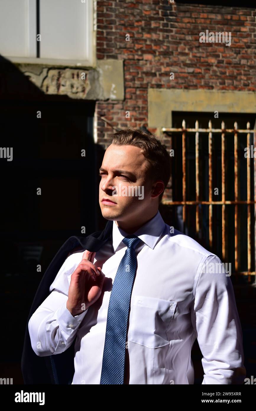 Young muscular white man carrying his black suit jacket over his ...