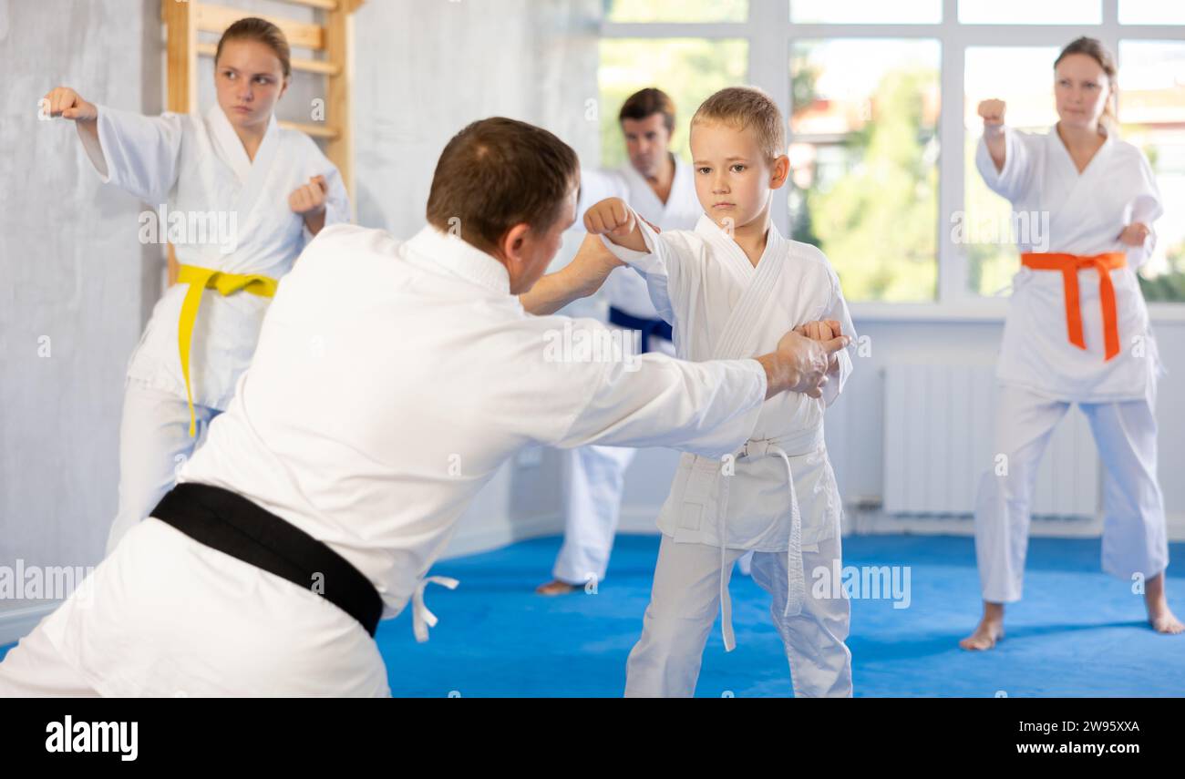 Teacher corrects boy pupil pose posture position of body, hands, legs ...