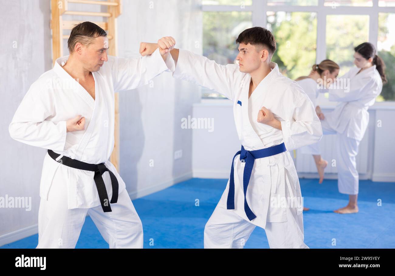 Young male attendee of karate classes fighting with middle-aged man in ...