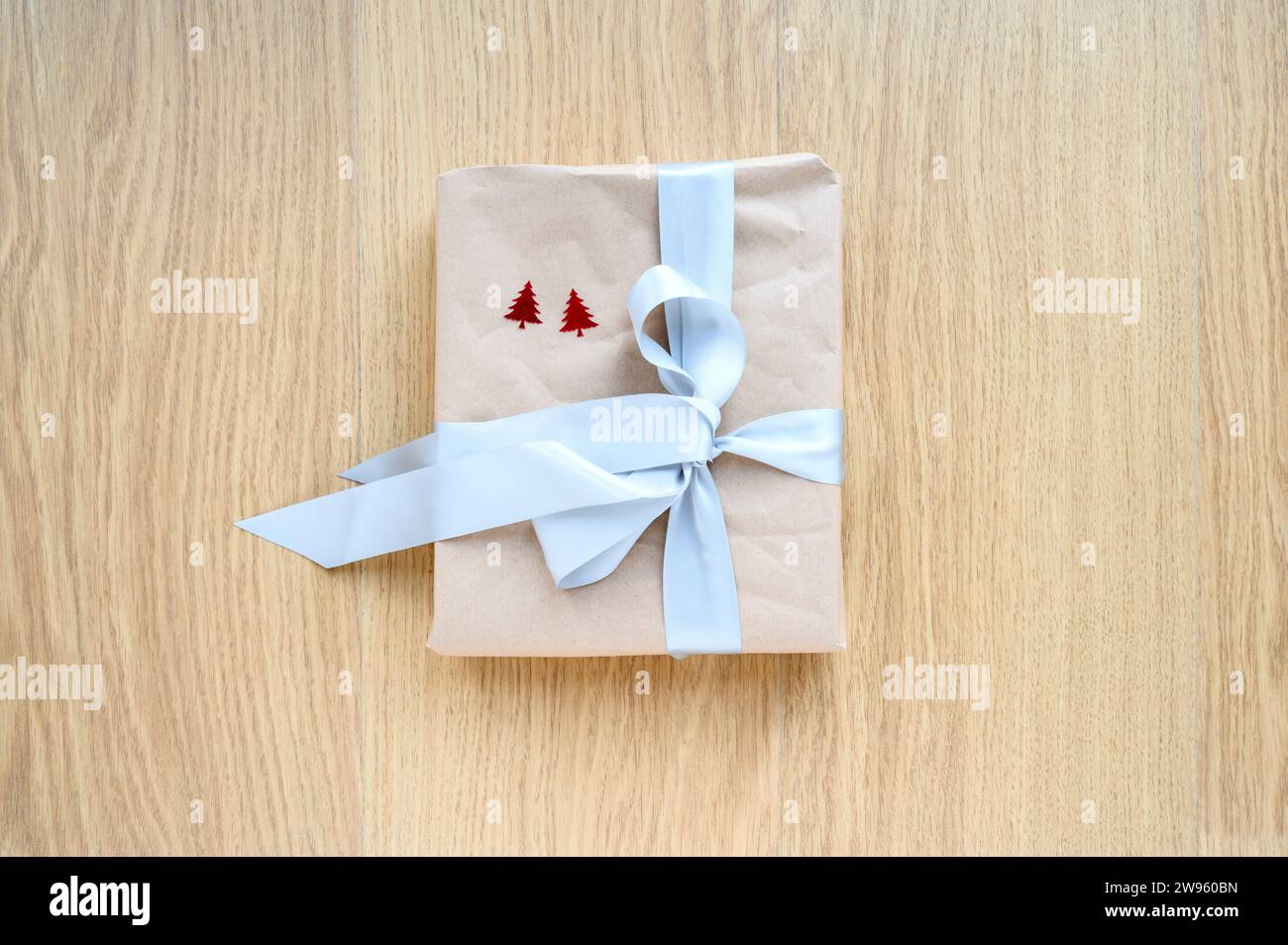 Christmas gift parcel wrapped in brown paper and tied up with a blue ...