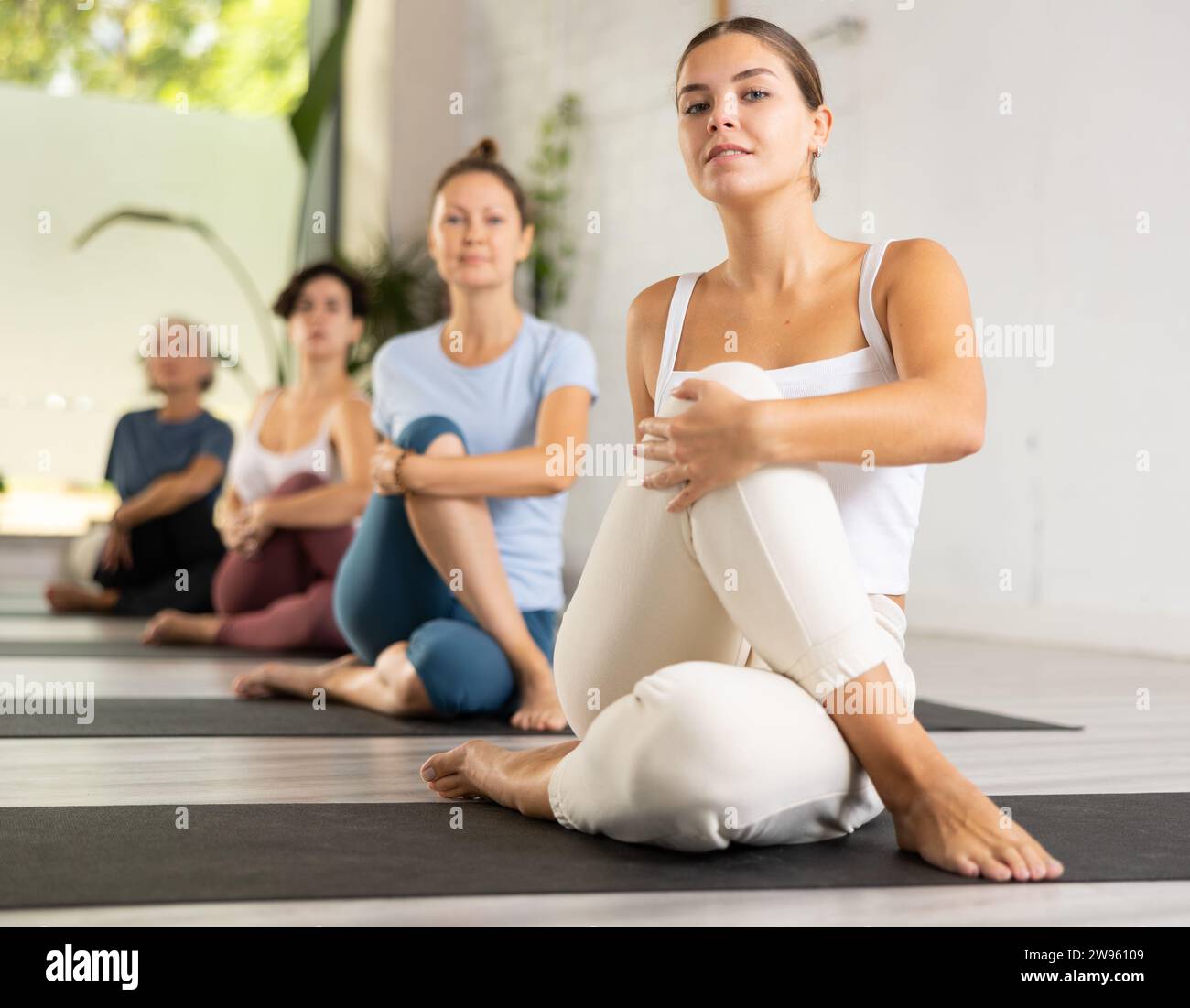 Calm female gym visitor twisting in Ardha Matsyendrasana pose during ...