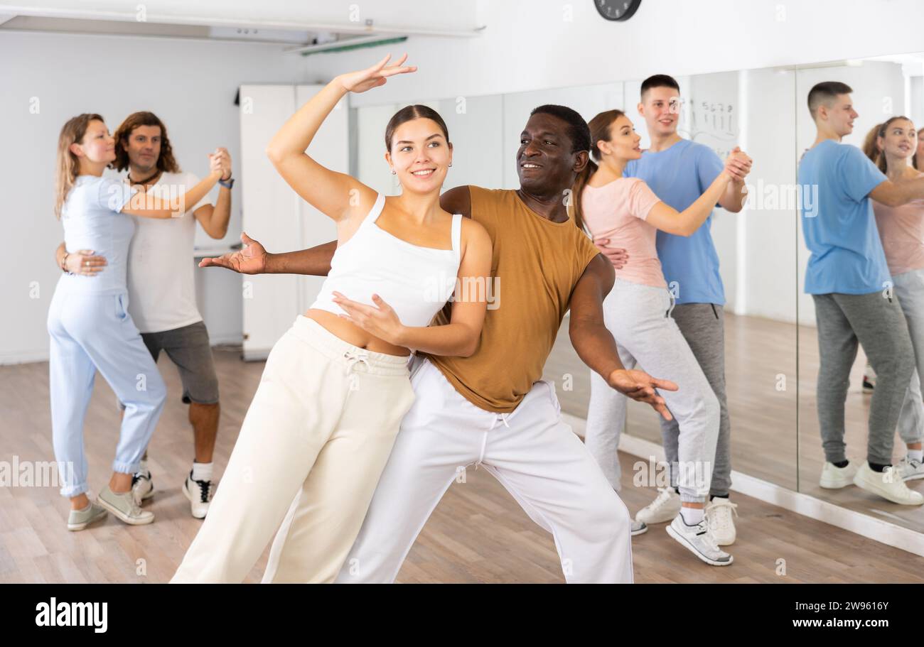 Woman and man practicing modern dance moves in pair during group class ...