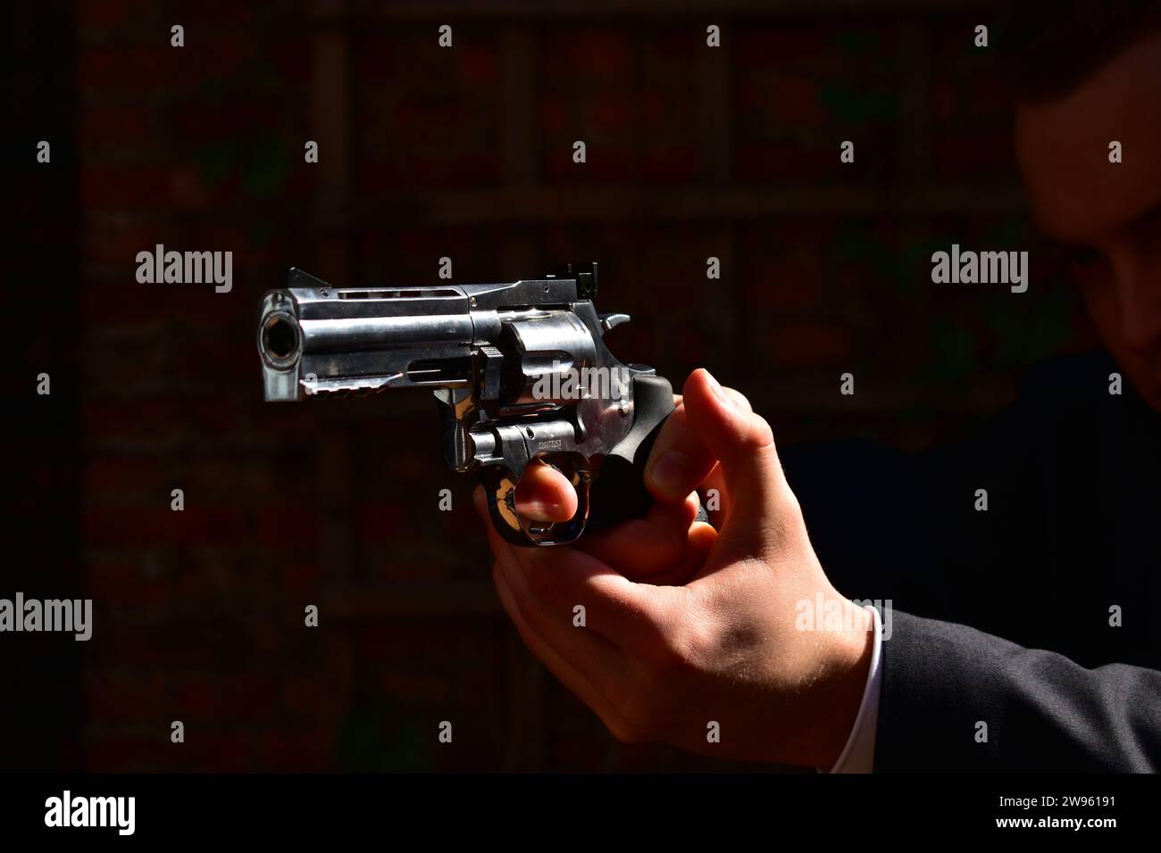 Close-up of a chrome revolver with a finger on the trigger of a white ...