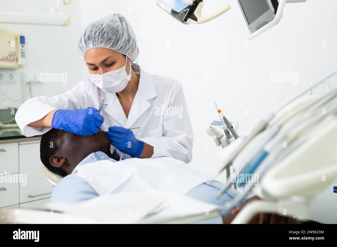 Orthodontist using tools and curing toothache of african-american man ...