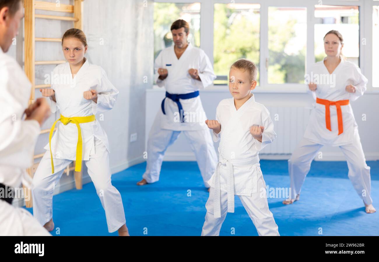 Boy with his family in kimonos and colored belts practicing karate with ...