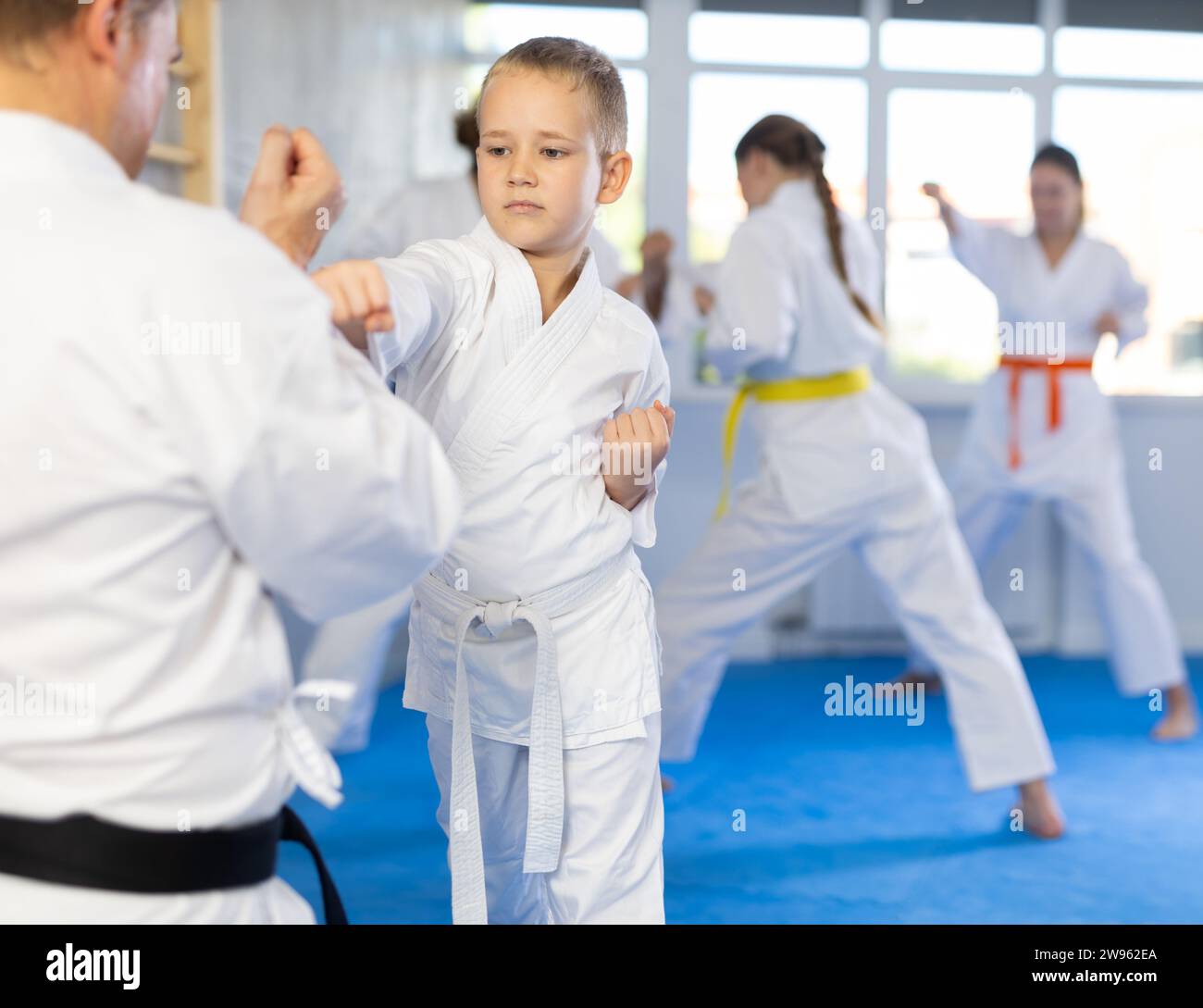 Boy at group training in gym practice karate punch block technique with ...