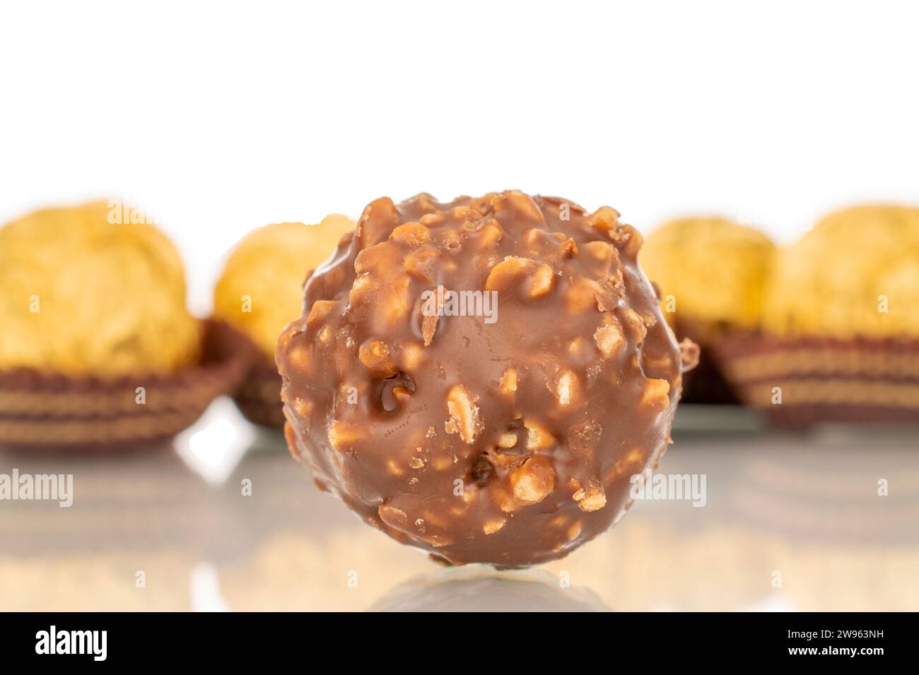 Several chocolate candies with nuts in a paper wrapper, macro, isolated ...