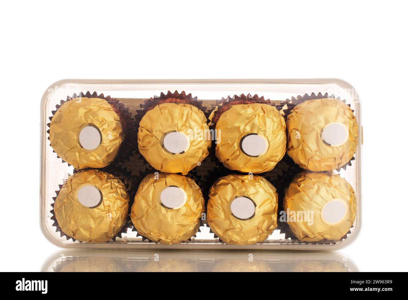 Several chocolate candies with nuts in a paper wrapper in a plastic box ...