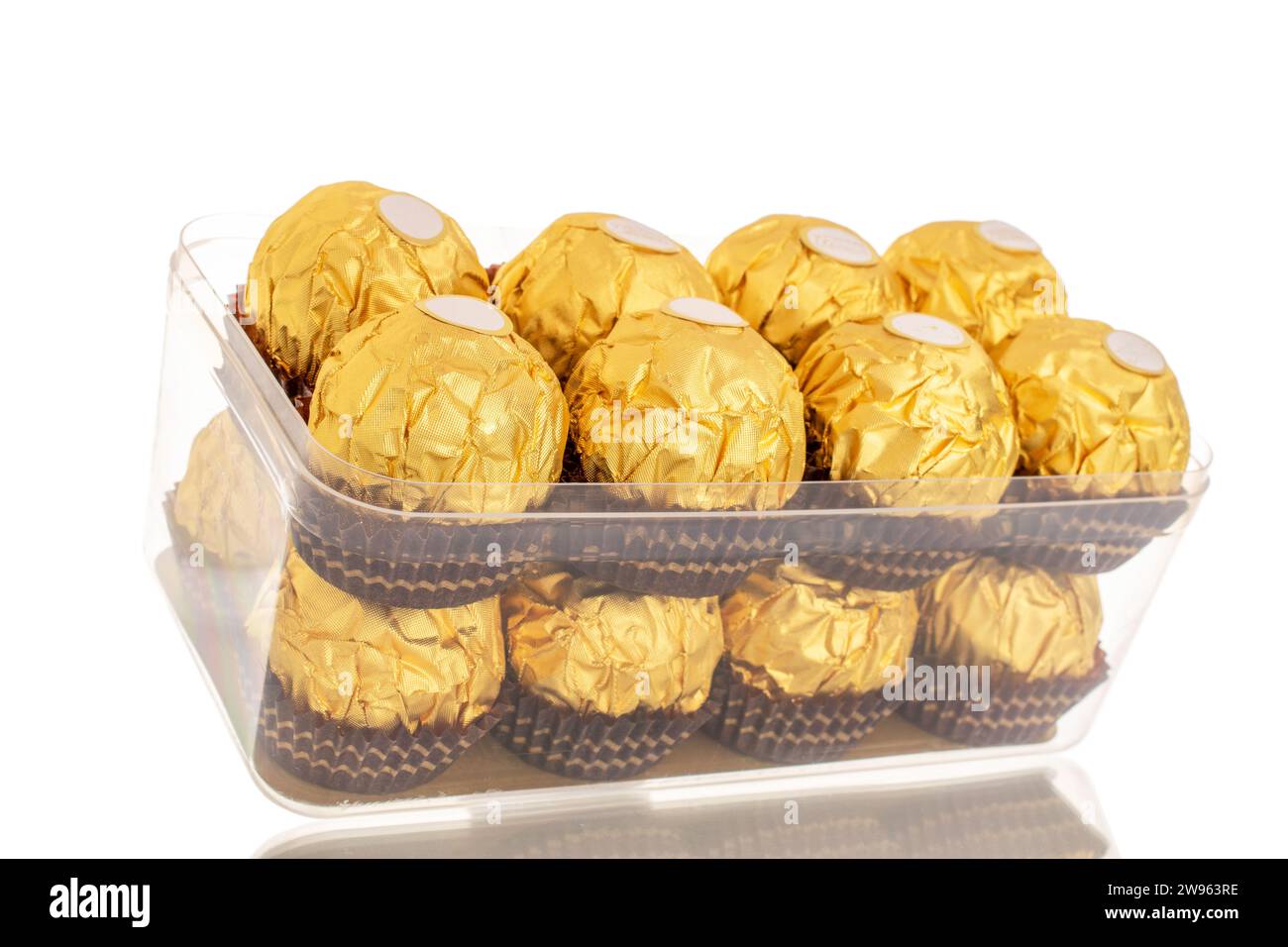 Several chocolate candies with nuts in a paper wrapper in a plastic box ...