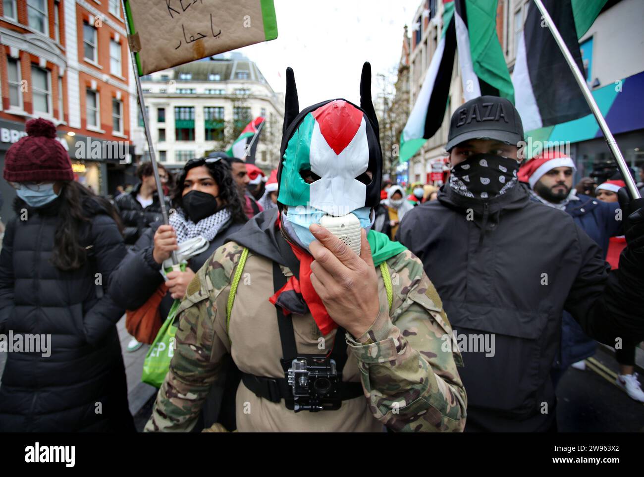 London, UK. 23rd Dec, 2023. A protester wears a Batman-like hood with ...