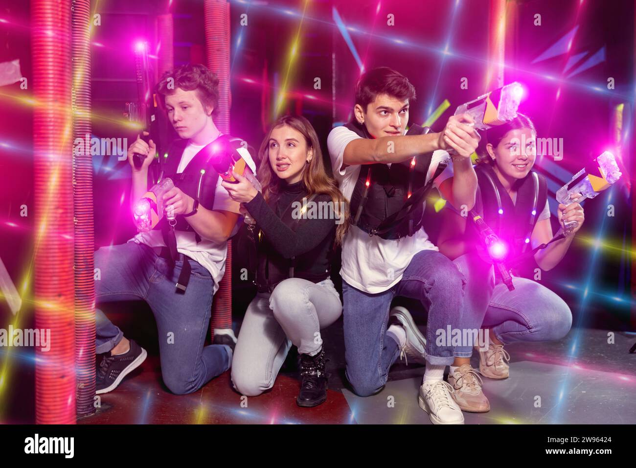 Laser tag players young mens and womens playing in teams in dark laser ...