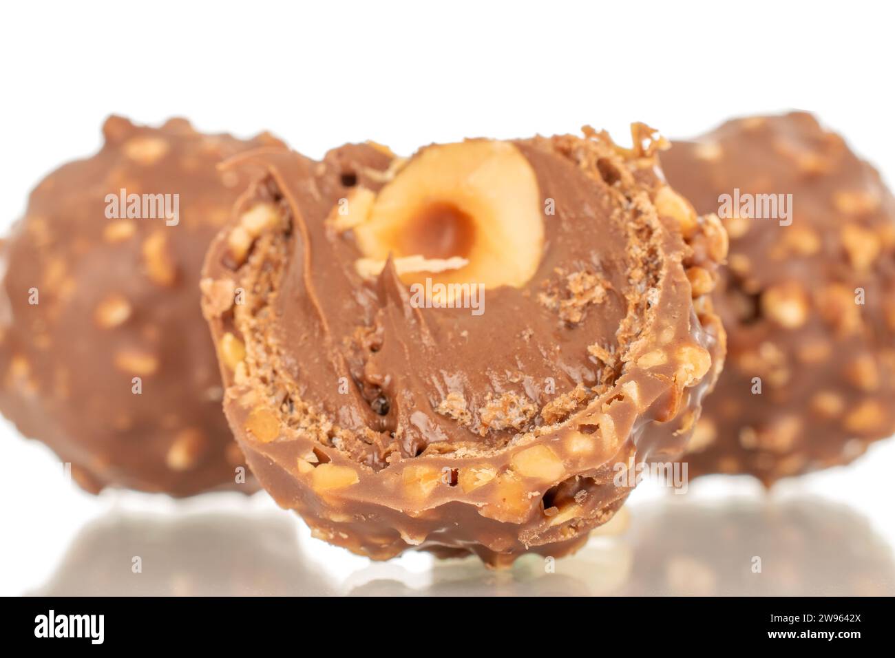 One half of chocolate candy with nut and two whole candies, macro ...