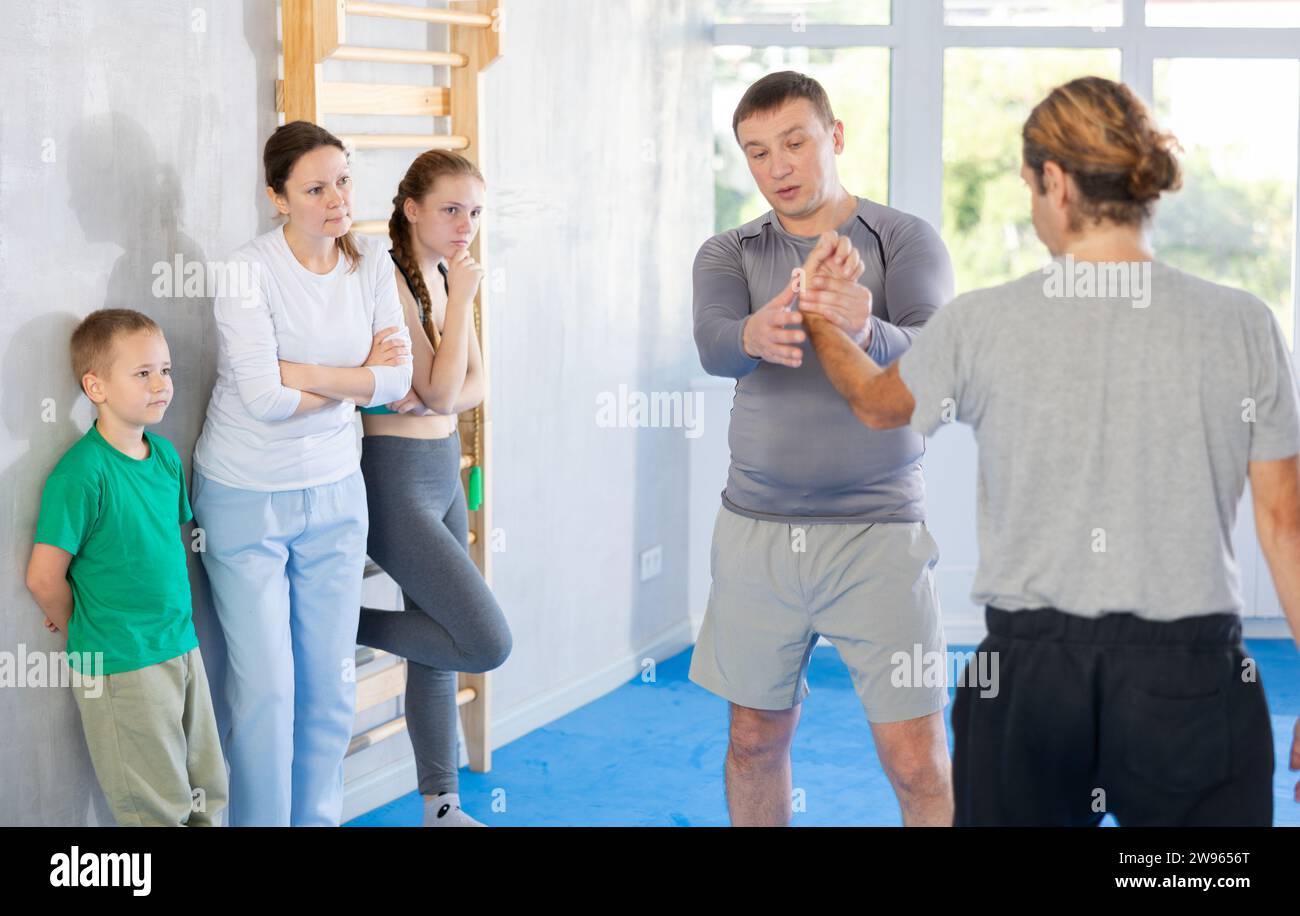 Man coach shows family students technique of performing painful modus ...