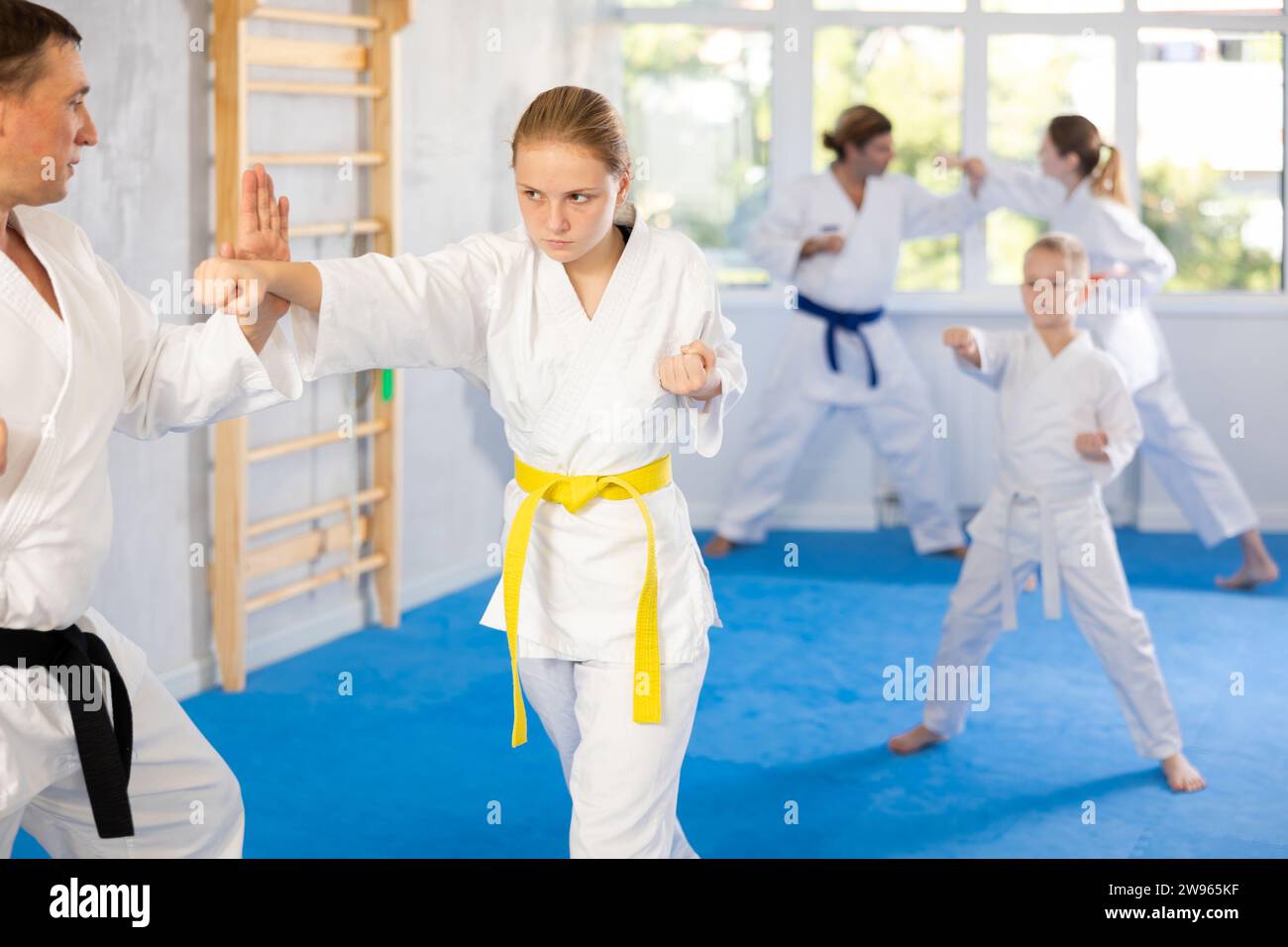 Teen girl at group training in gym practice karate punch block ...