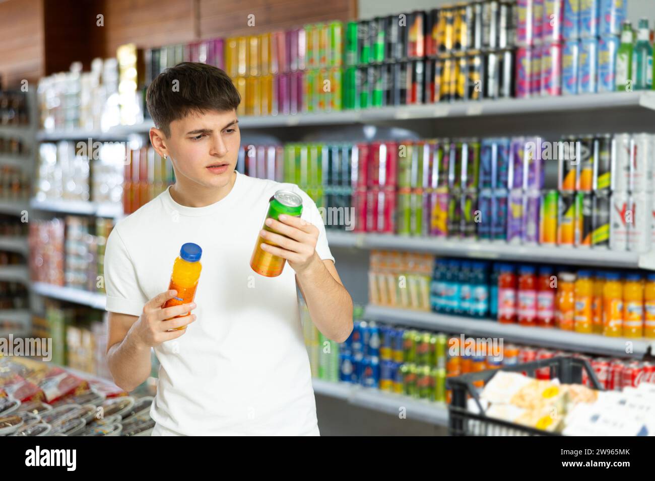 Guy chooses drinks by reading labels on bottles in supermarket ...