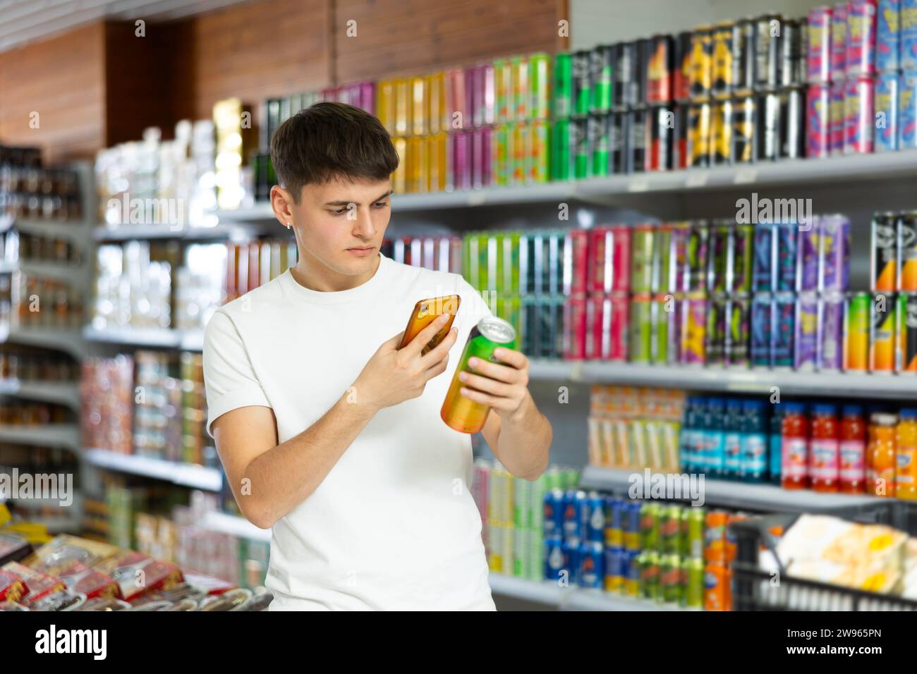Guy scans bar code from label of an aluminum can with drink in grocery ...