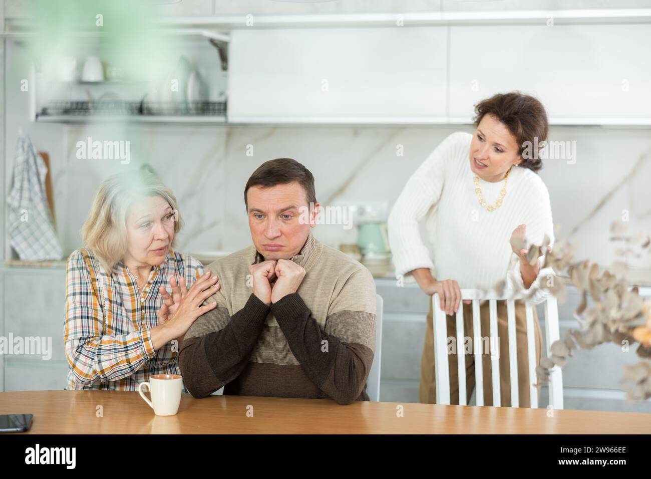 Family members quarreling in the kitchen and old woman trying to calm ...