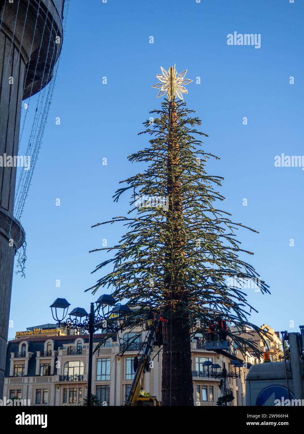 Installation of an outdoor Christmas tree. Workers on a crane install ...
