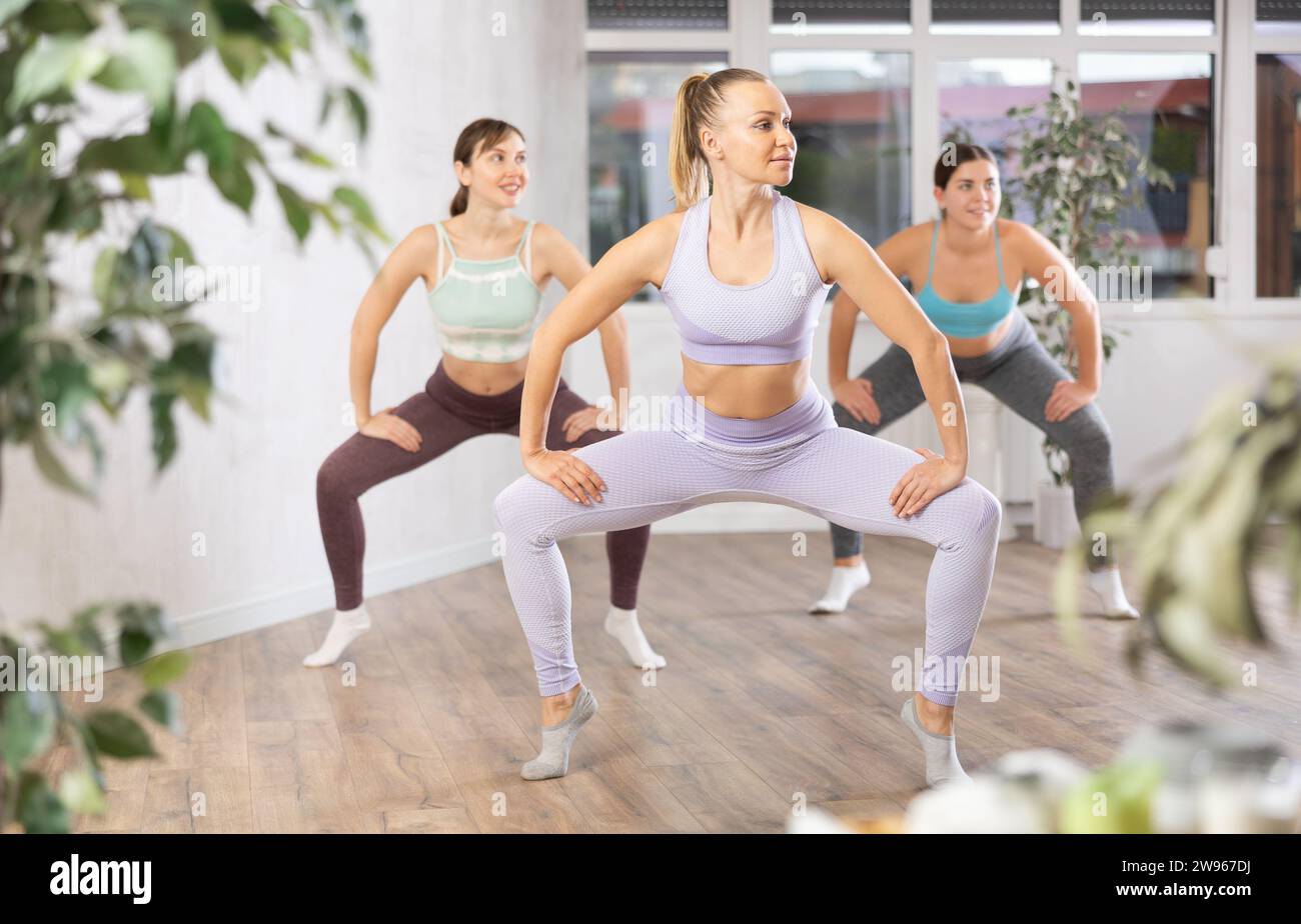Group of young energetic women in tight activewear warming up with ...