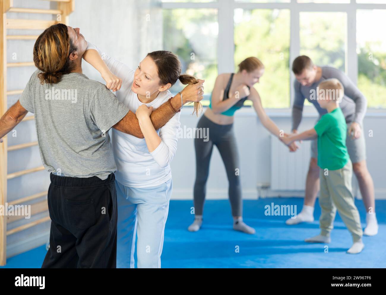 Woman practicing self-defense strikes chin with hands in sport club ...