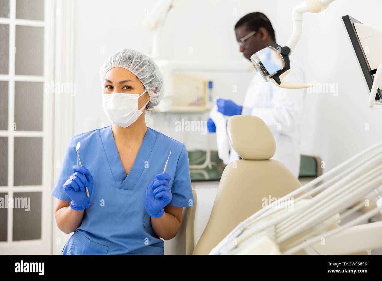 Female dentist standing in dental office with tools in hands Stock ...