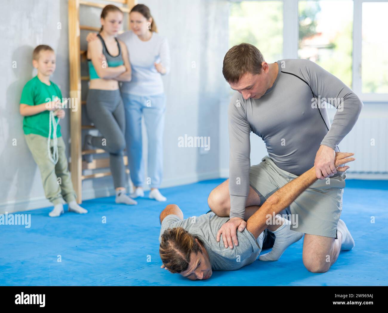 Trainer and man are training in gym practicing hand grab technique ...
