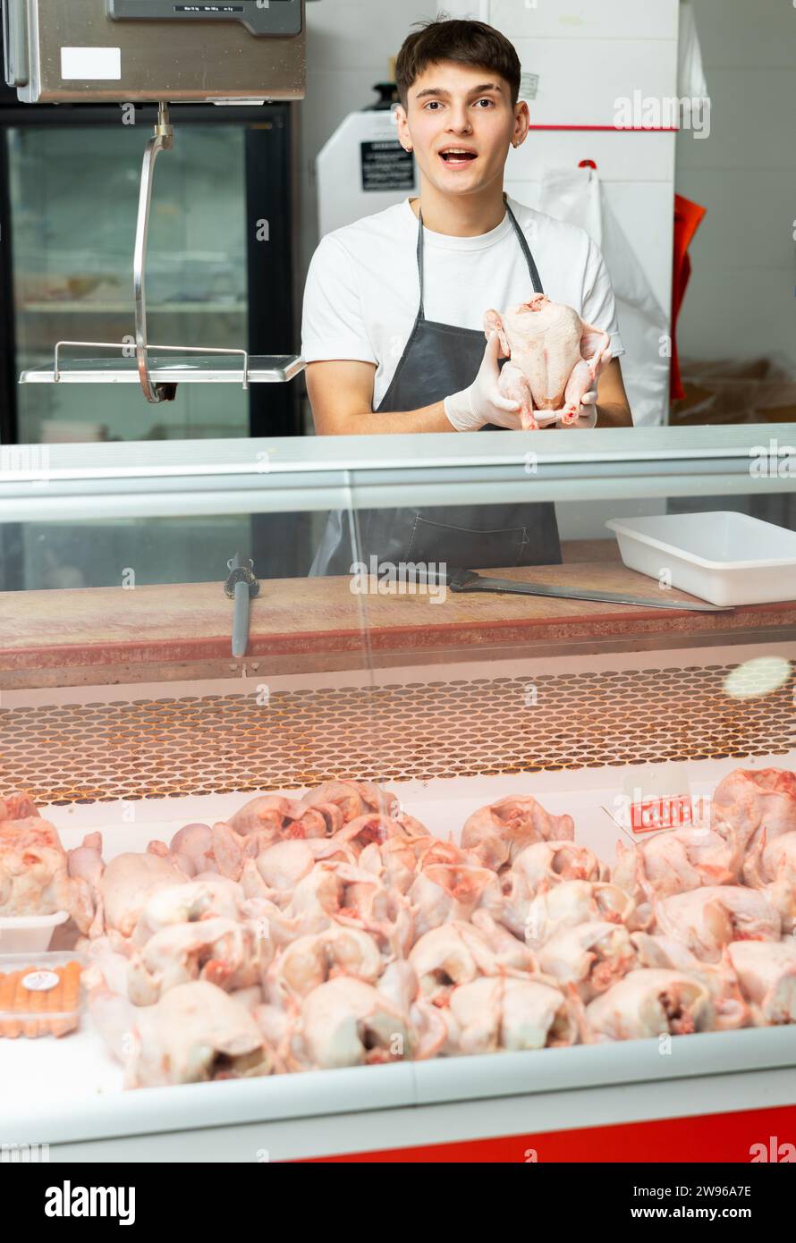 Portrait of grocery store salesman putting chicken carcasses on display ...