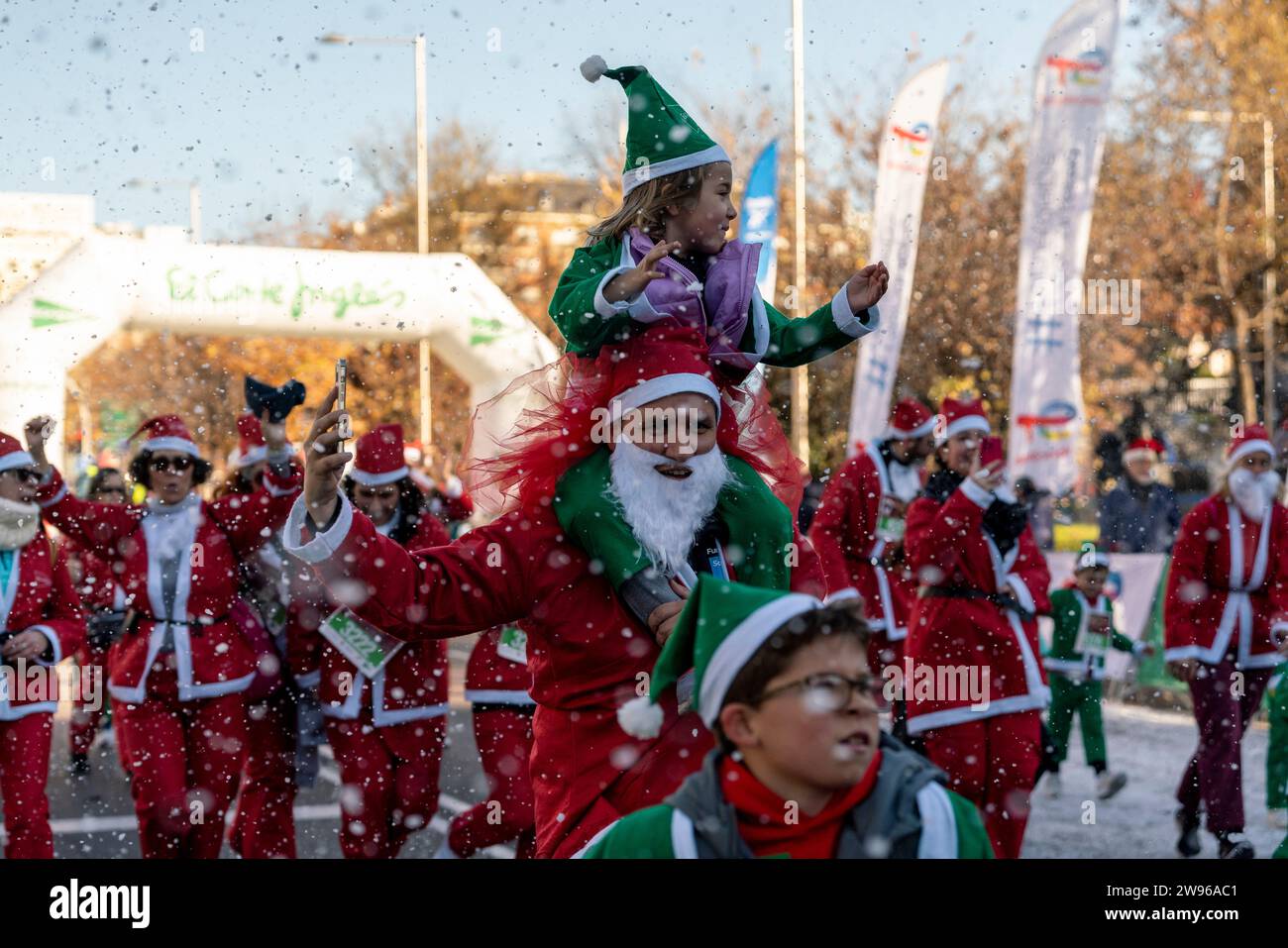 A man dressed as Santa Claus carrying a child in his shoulders arrives ...
