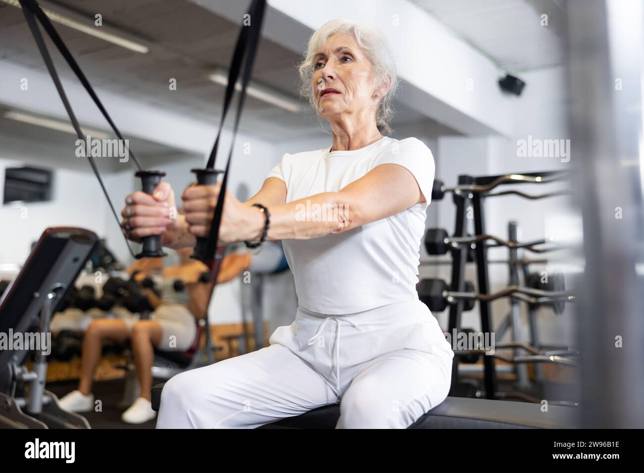 Active athlete mature woman during exercises on crossover exercise ...