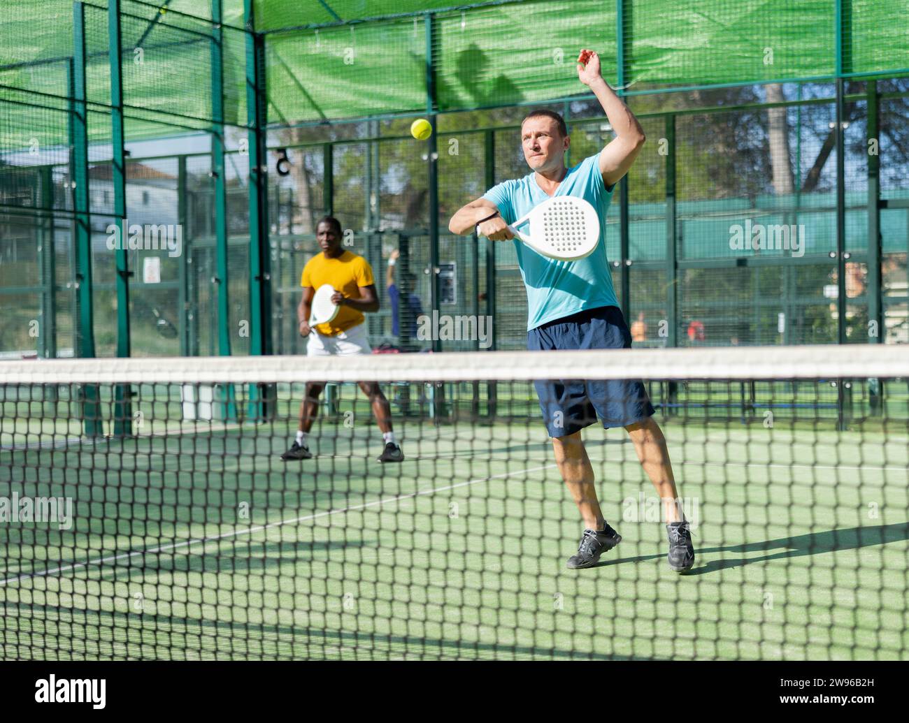 Male padel tennis player training on court. Man using racket to hit ...