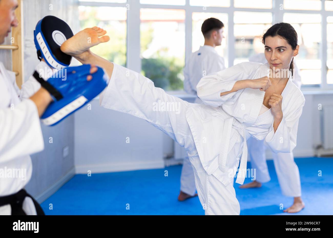 Young woman karateka in kimono trains kicks in studio Stock Photo - Alamy