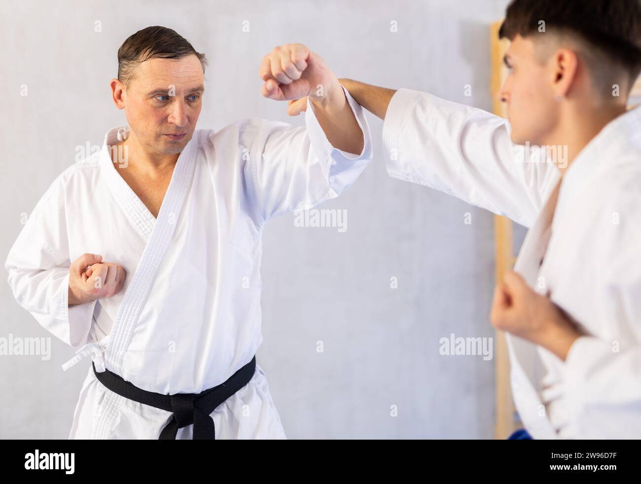 Adult man and young guy karatekas train karate techniques in group in ...