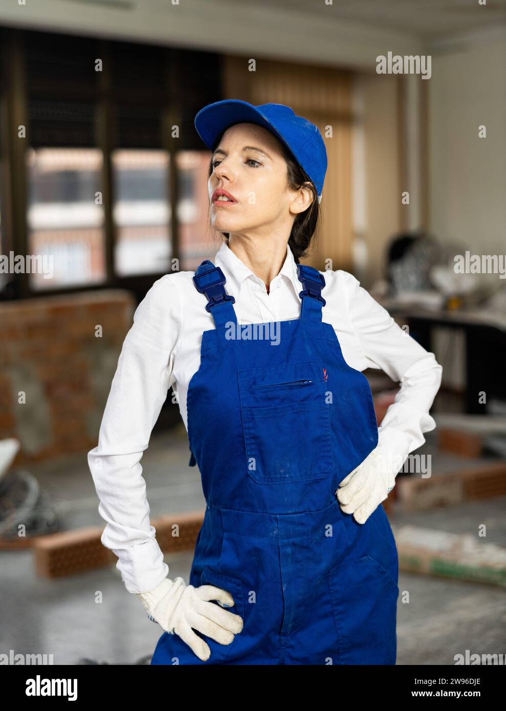 Woman foreman in blue overalls posing in a house under construction ...