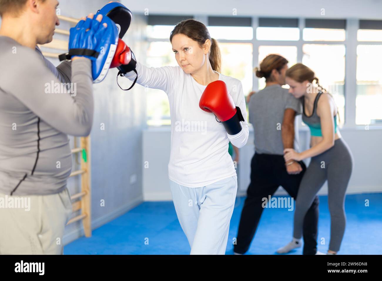 Woman works out strength and speed of boxing punch mitts with help of ...