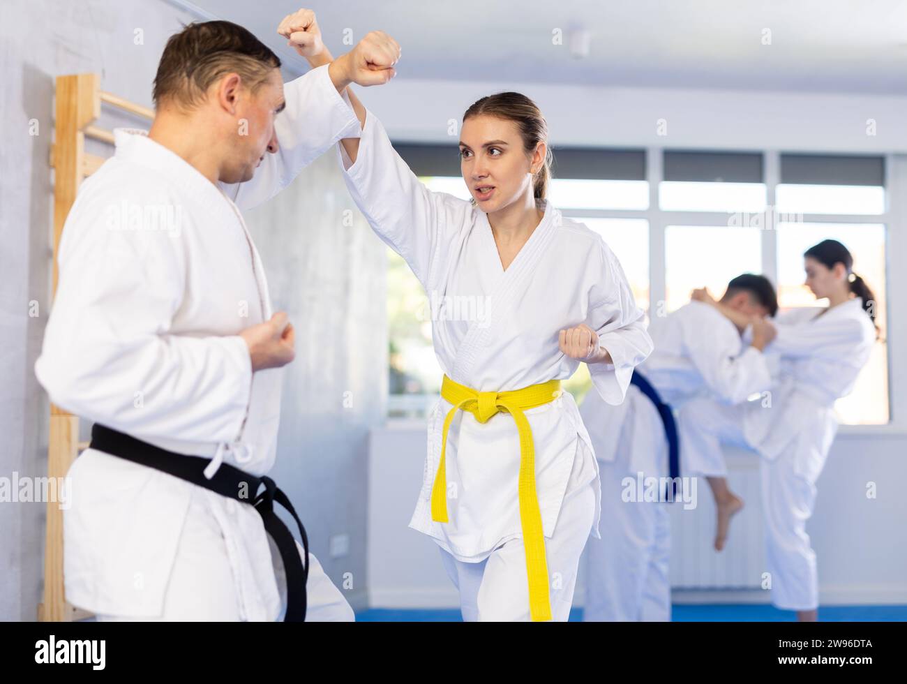 Diligent young woman practicing karate techniques with middle-aged man ...