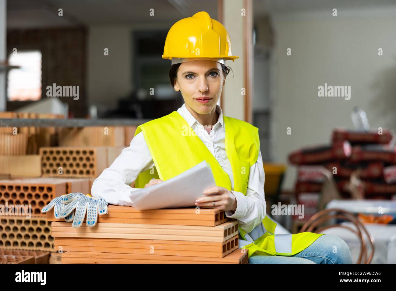 Focused female civil engineer in yellow uniform making notes while ...