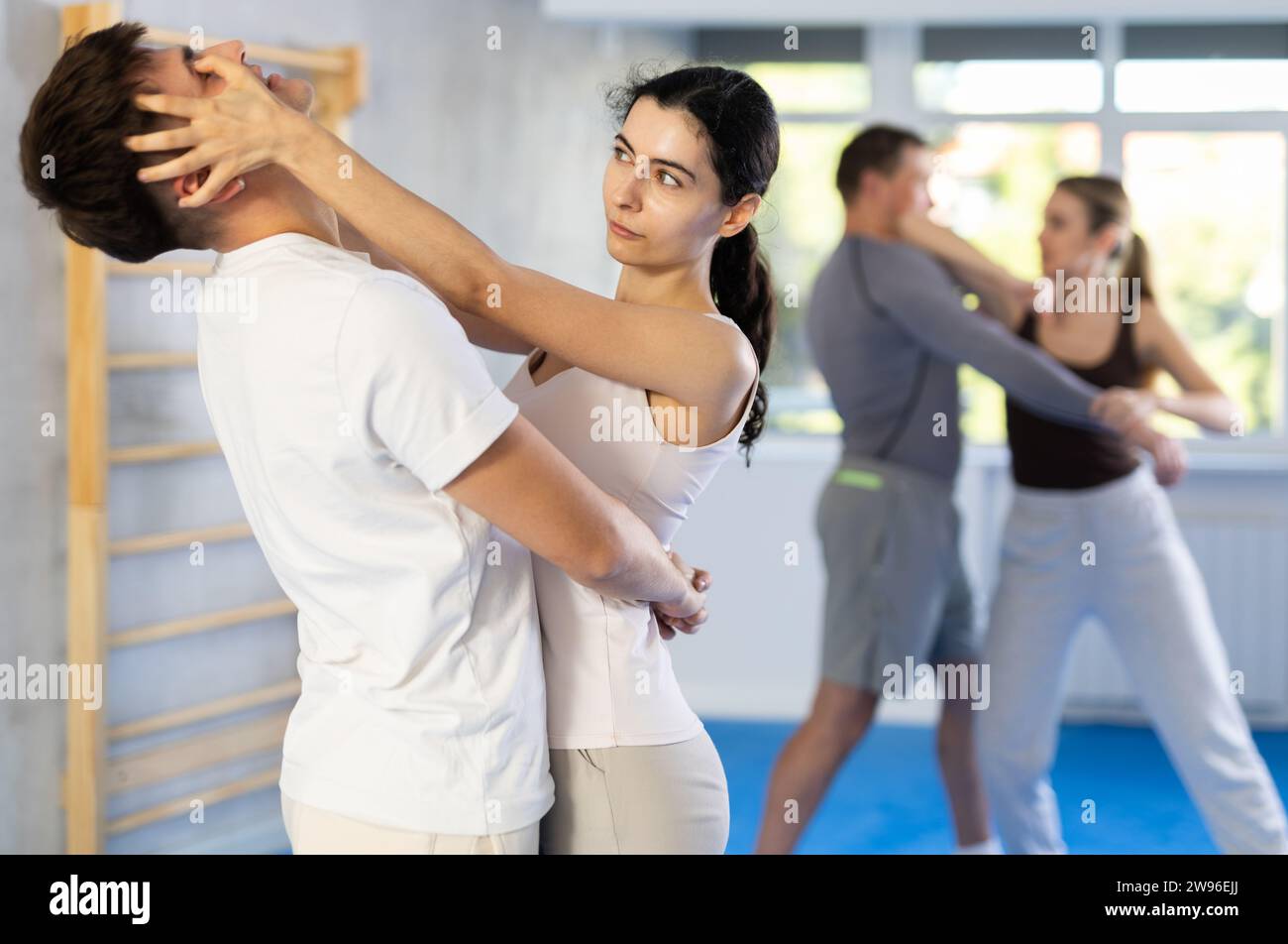 Aggressive young woman practicing self-defense techniques in pairs with ...