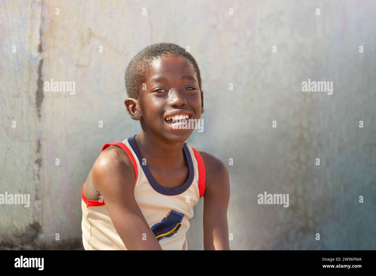 african child in a village, he is standing in front of the house ...