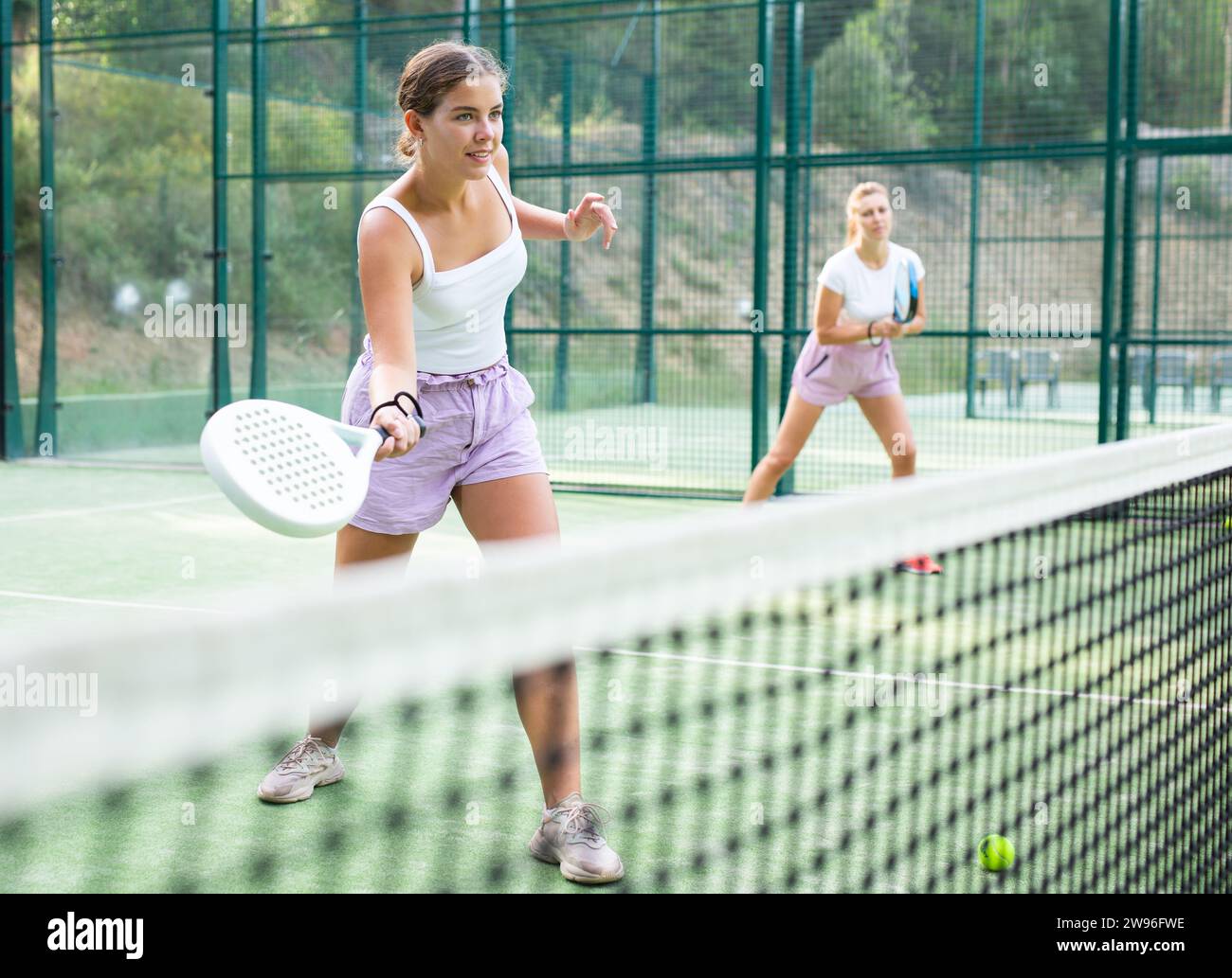 Two active women tennis players, playing padel on an outdoor court ...
