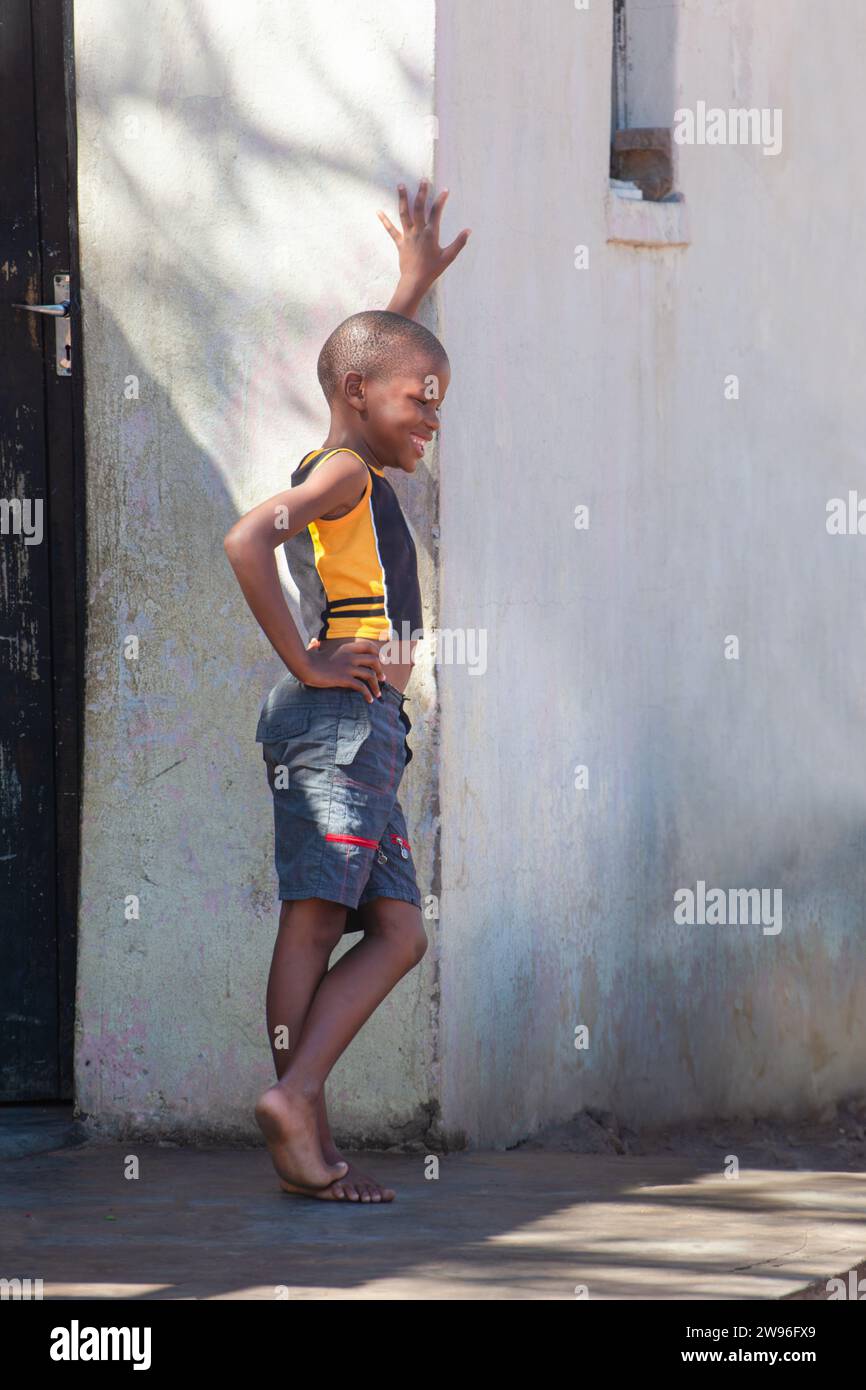 african child in a village, he is standing in front of the house ...
