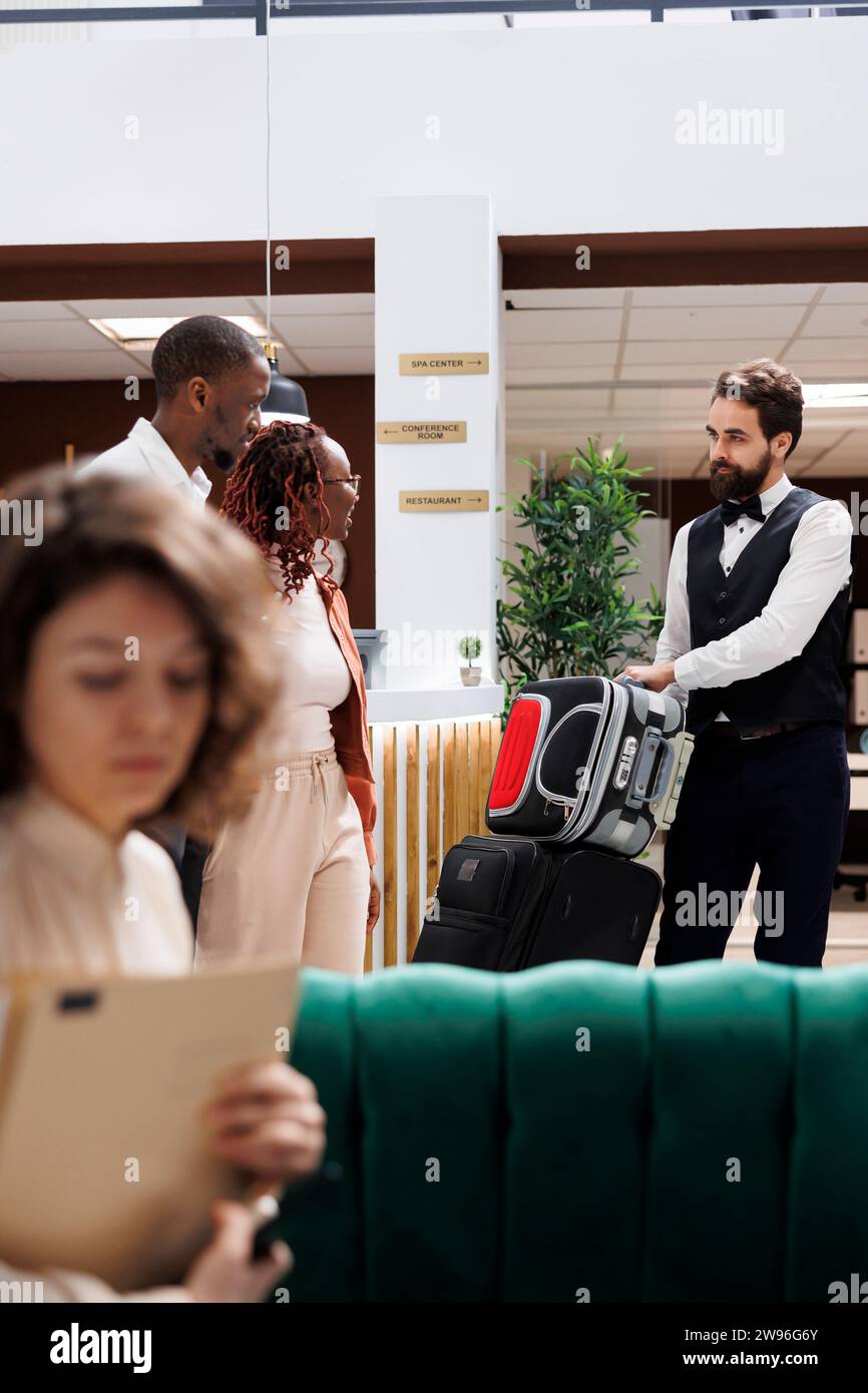 Male employee helping clients with bags, carrying luggage for people ...