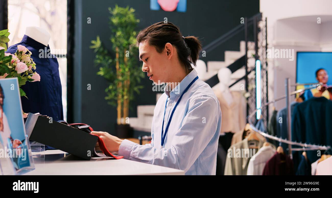 Asian manager arranging stylish accessories, working at modern boutique ...