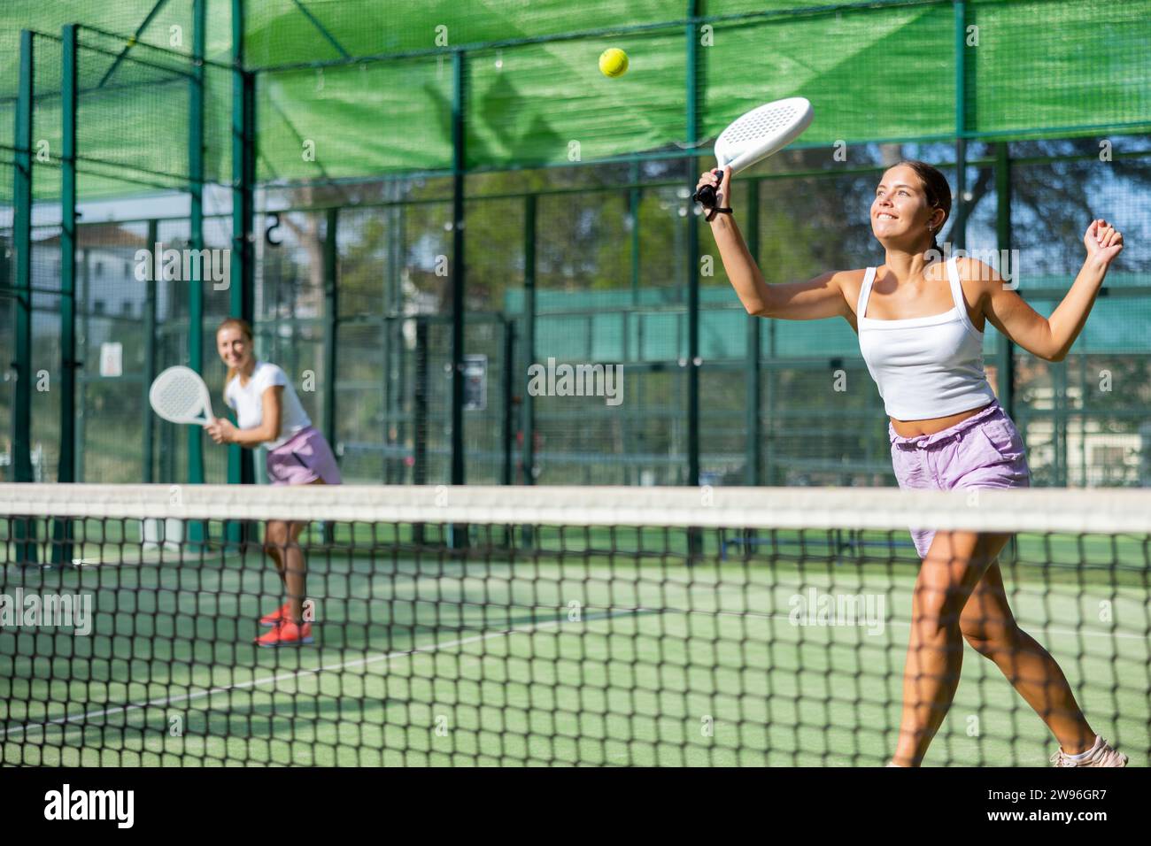 Two active women tennis players, playing padel on an outdoor court ...